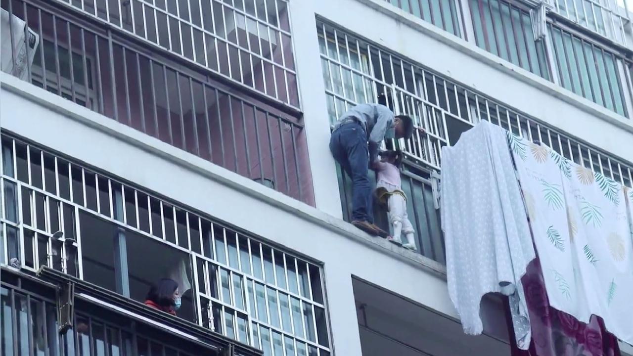 Man holds girl trapped on building ledge before firefighters arrive - CGTN