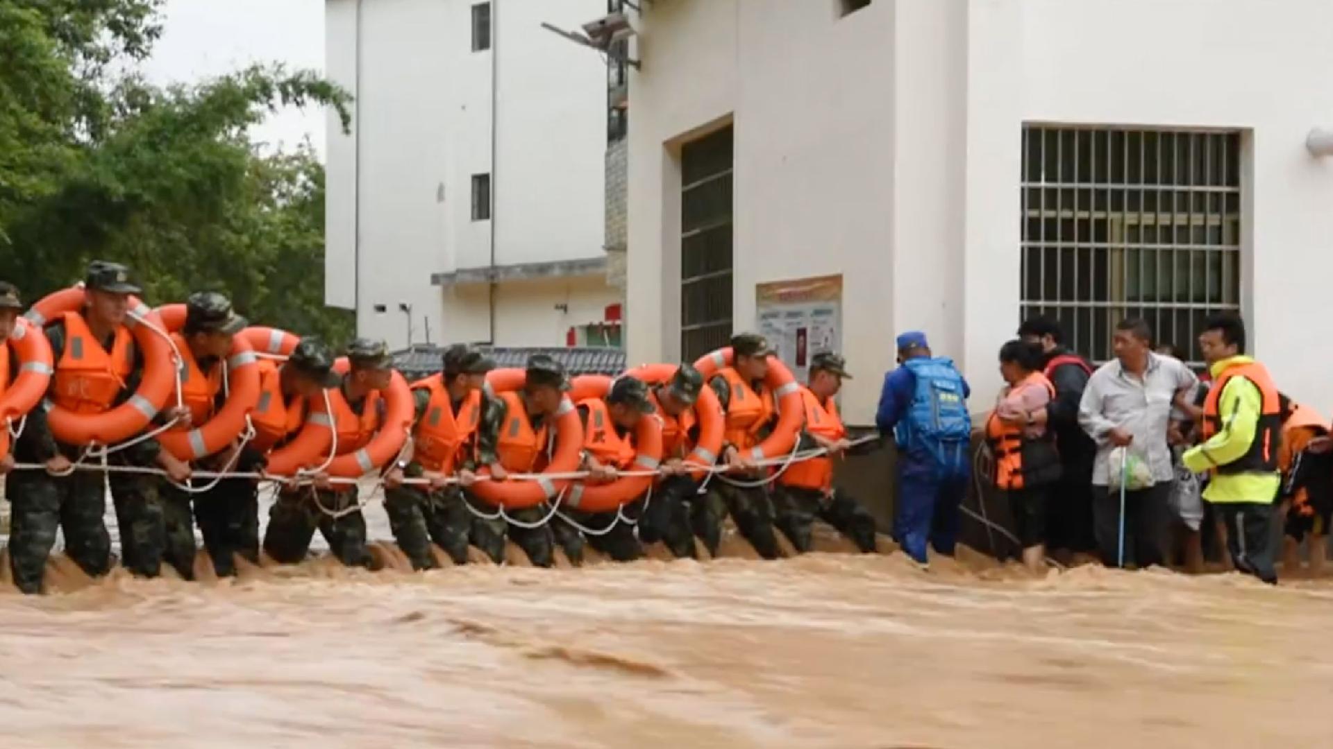 Armed police officers form human wall in flood to rescue people - CGTN