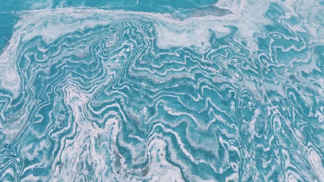 Winding ice cracks form stunning view on azure-colored frozen lake - CGTN