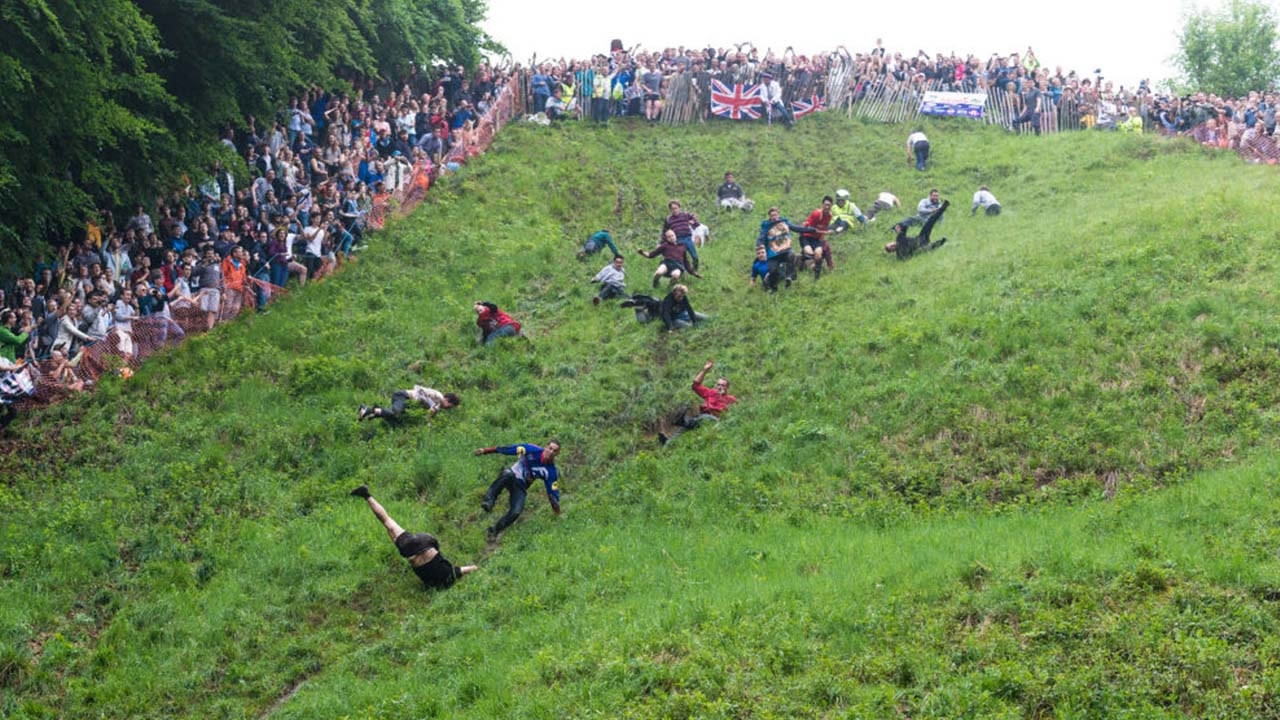 Thousands gathered to watch people chasing cheese down Cooper’s Hill in ...